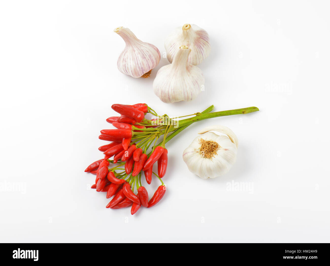 Bunch of small red chili peppers and garlic bulbs on white background ...
