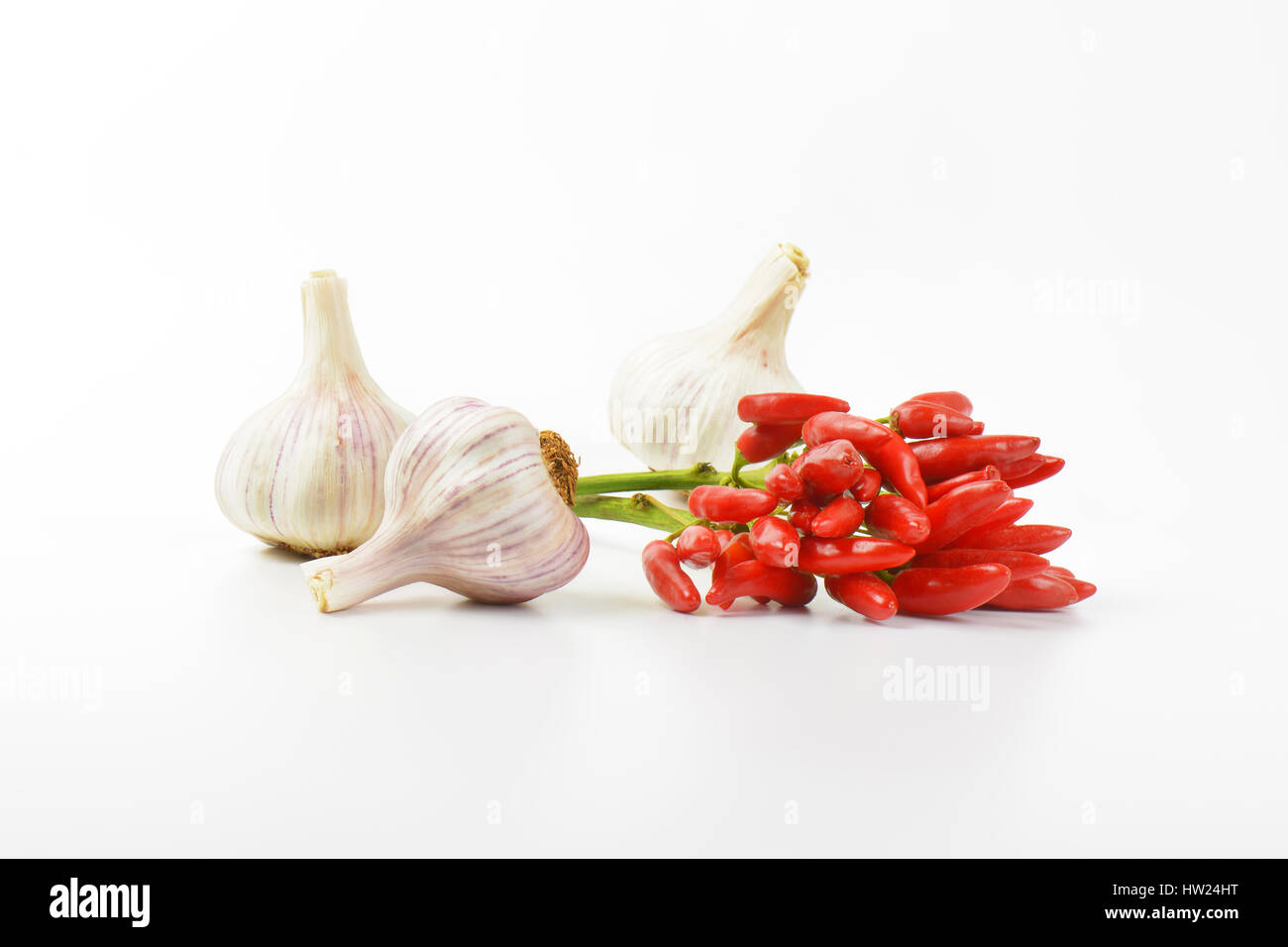 Bunch of small red chili peppers and garlic bulbs on white background ...