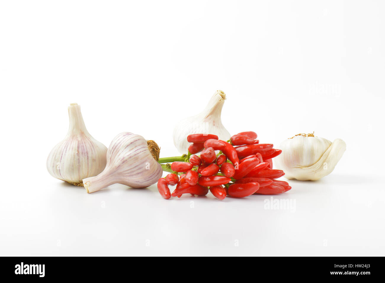 Bunch of small red chili peppers and garlic bulbs on white background ...