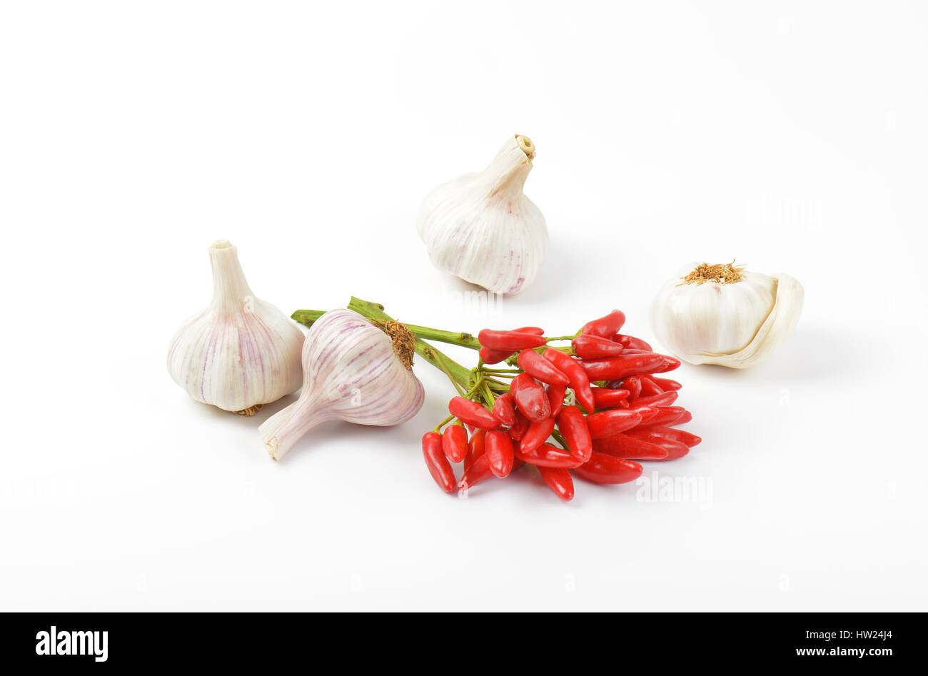 Bunch of small red chili peppers and garlic bulbs on white background ...