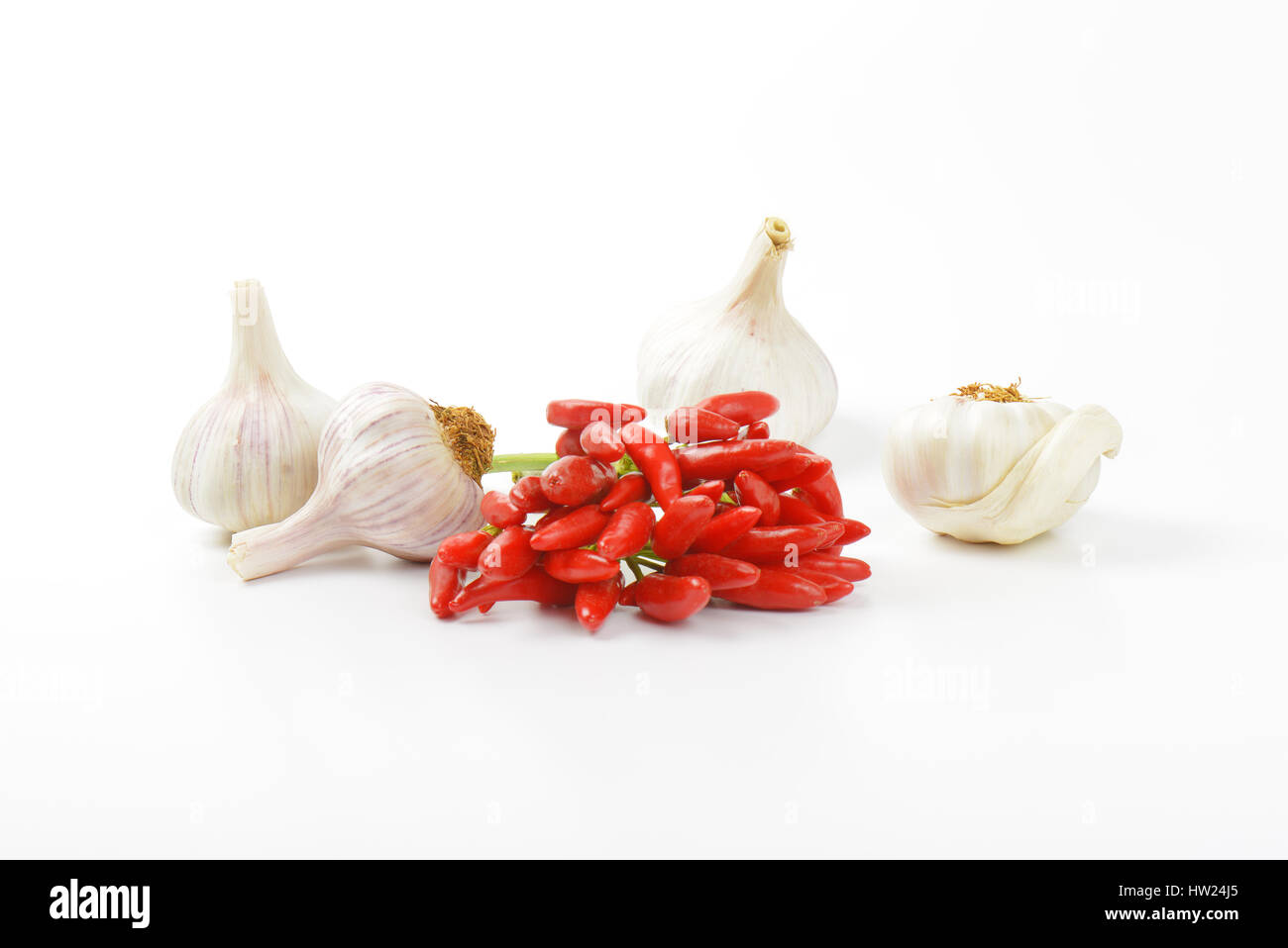Bunch of small red chili peppers and garlic bulbs on white background ...