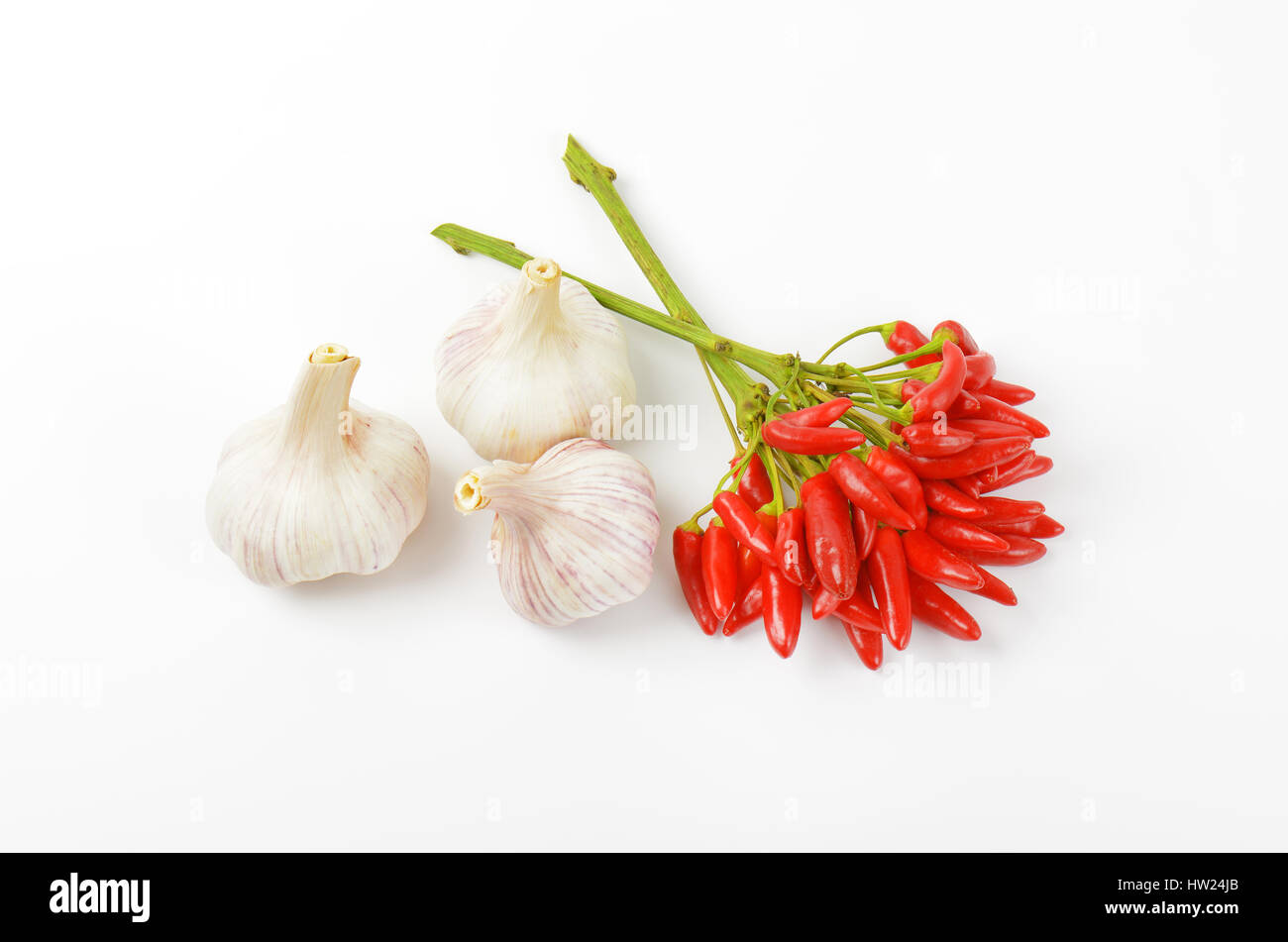 Bunch of small red chili peppers and garlic bulbs on white background ...