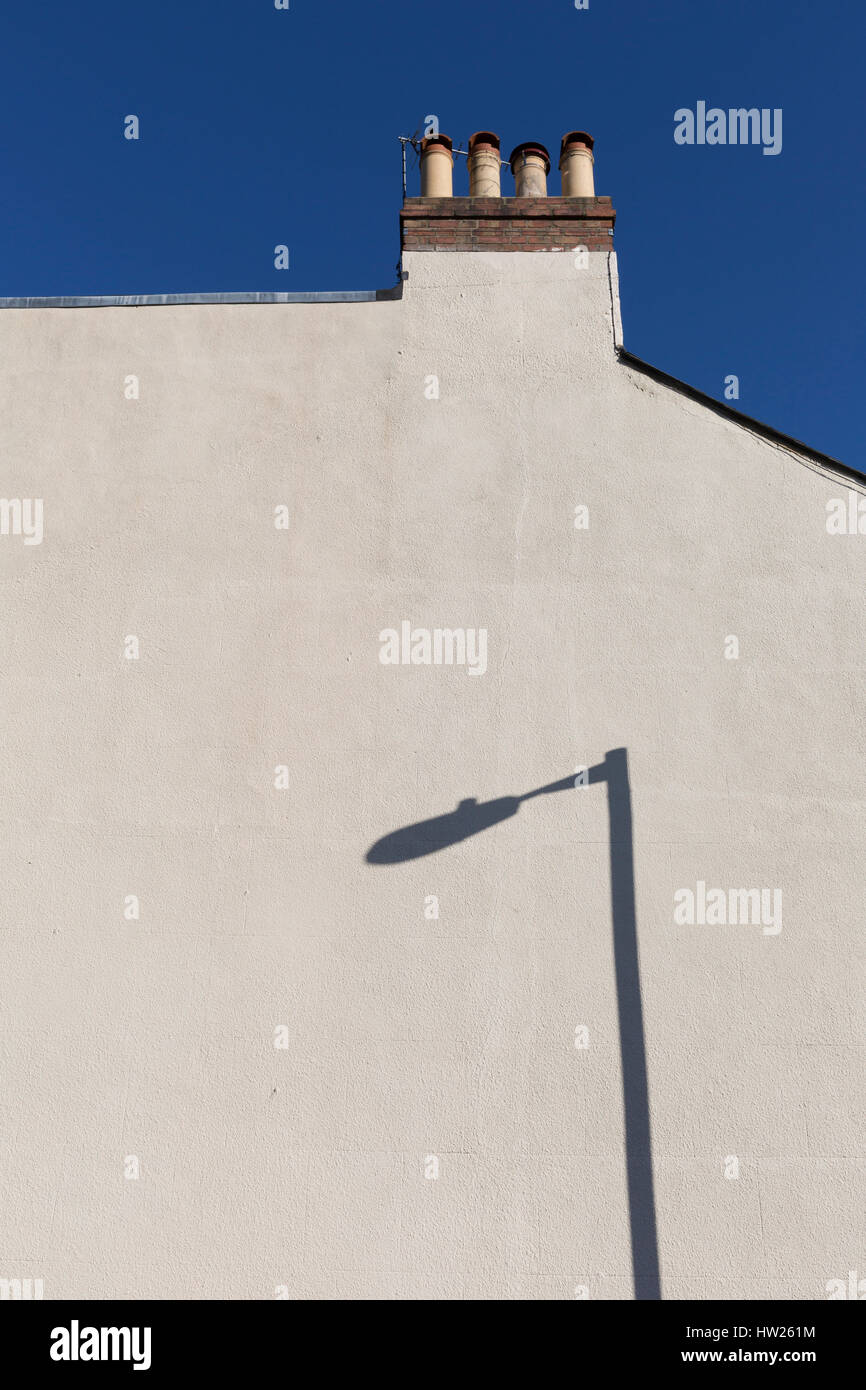 A shadow of a lamp post on the white outer wall of a house in East ...