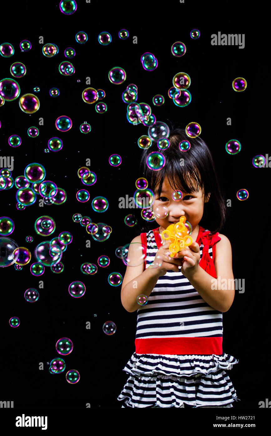 Asian Chinese children Playing Soap Bubbles in black background indoor ...