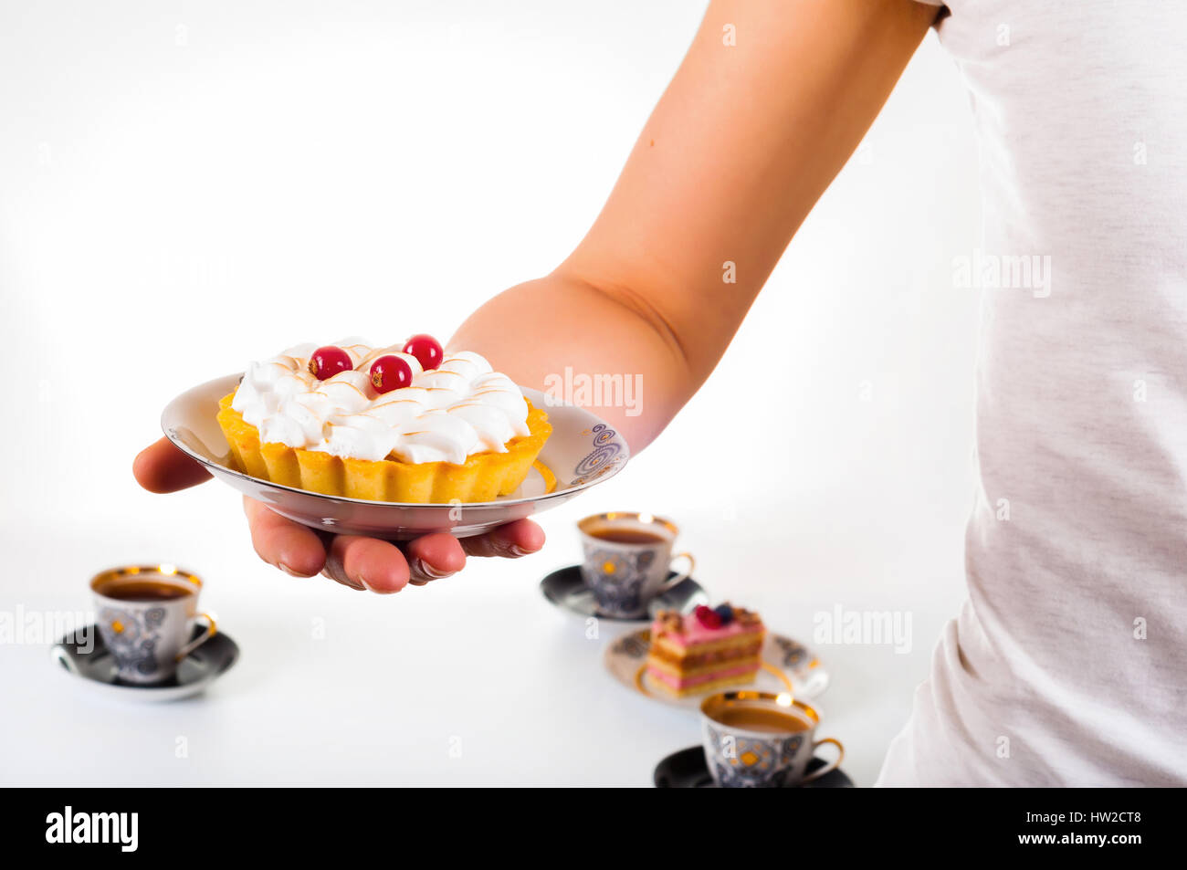 Woman's hand holding small cake on beautiful set plate Stock Photo - Alamy