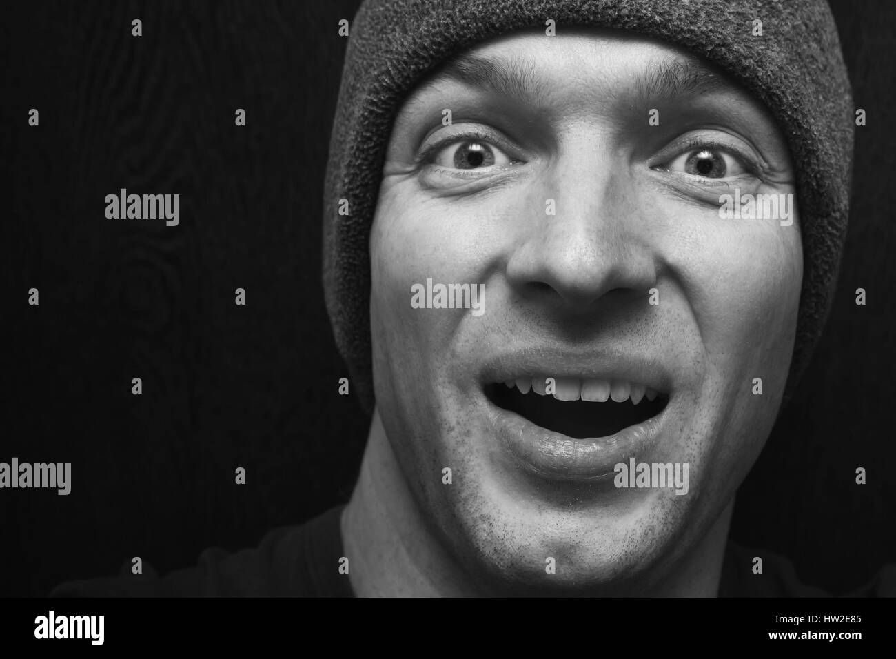 Young handsome smiling man in gray hat. Low key studio face portrait ...
