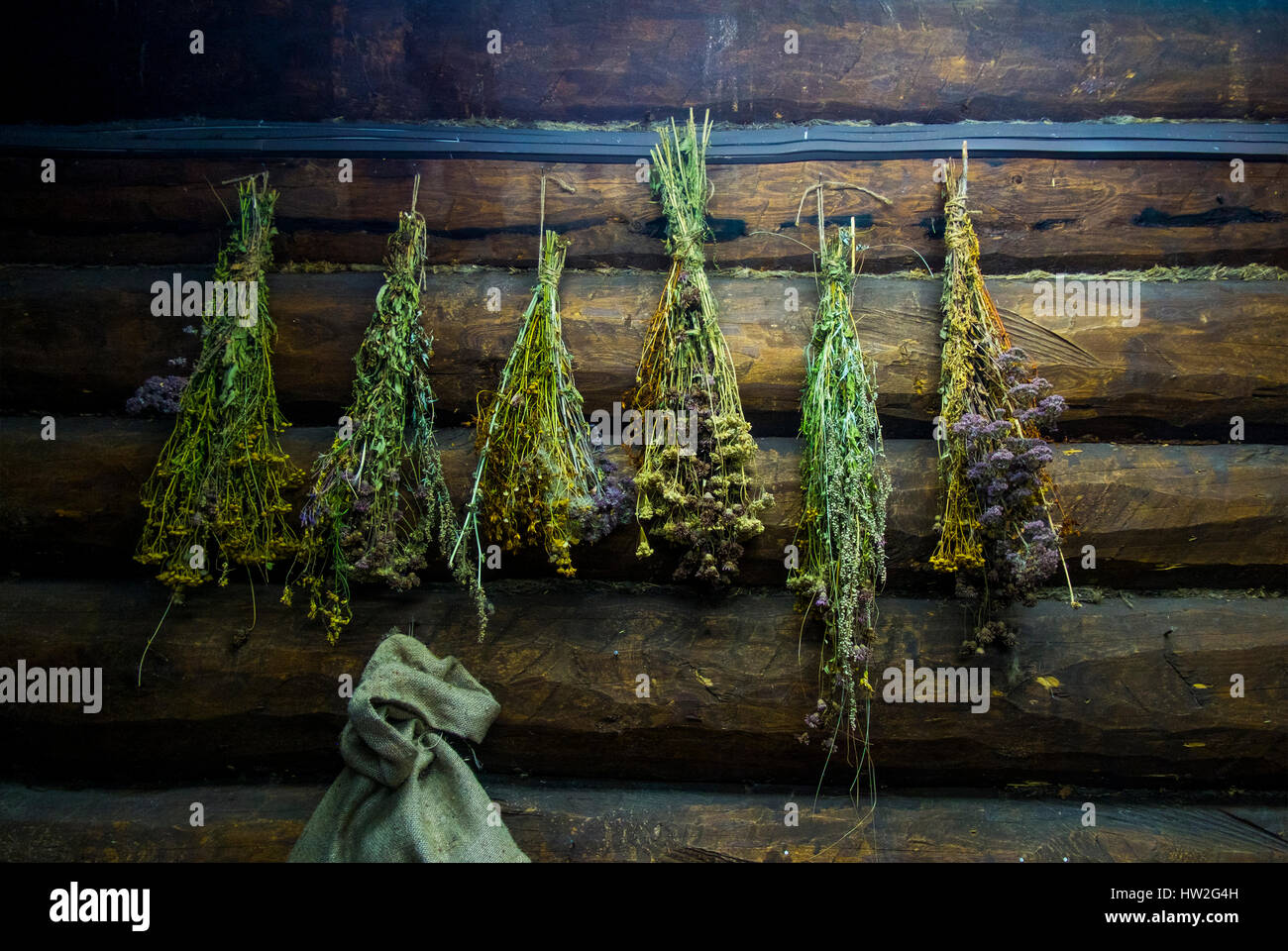 Green brooms hanging on log cabin wall Stock Photo - Alamy
