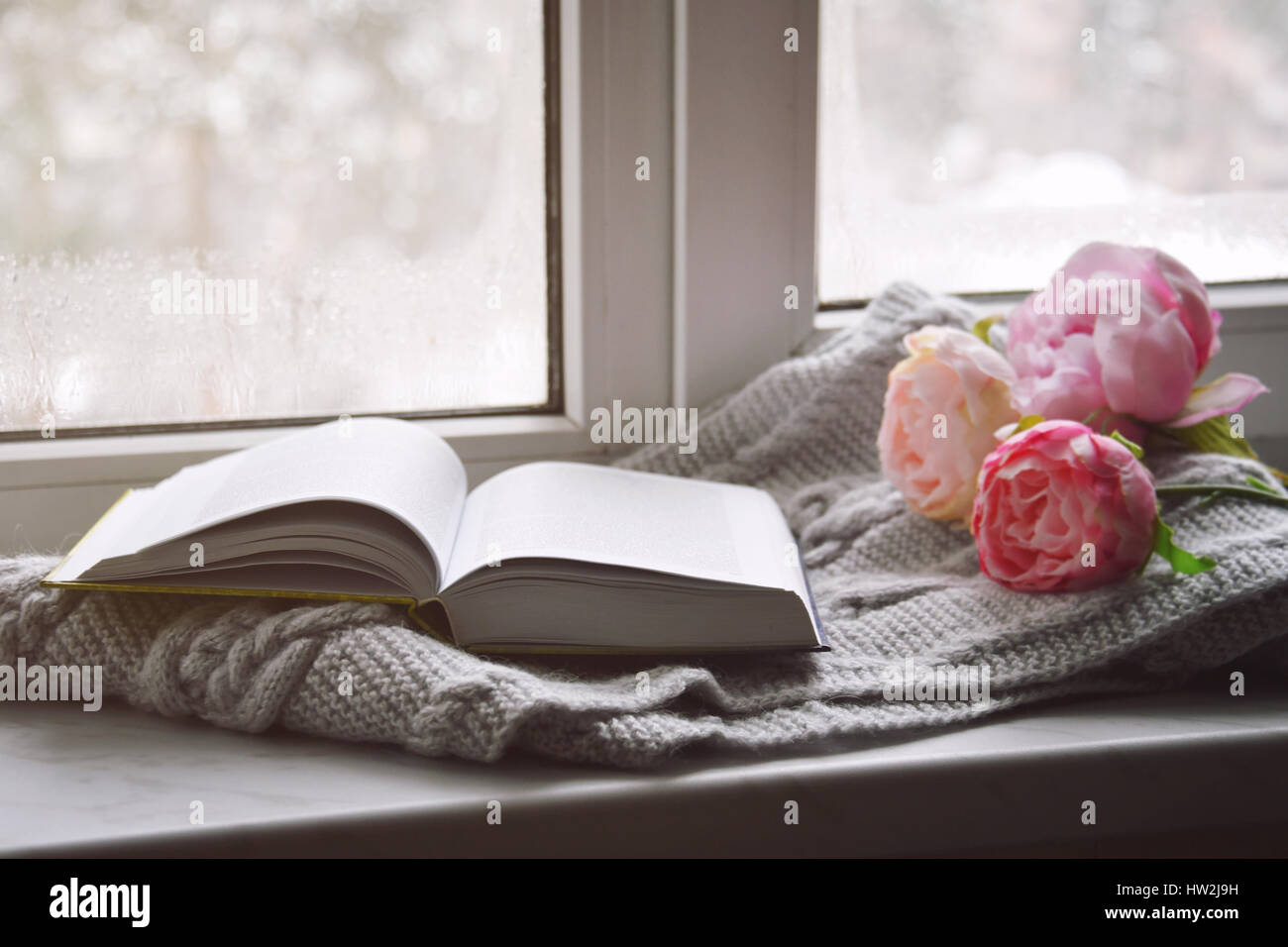 Cozy home still life: spring flowers and opened book with warm plaid on ...