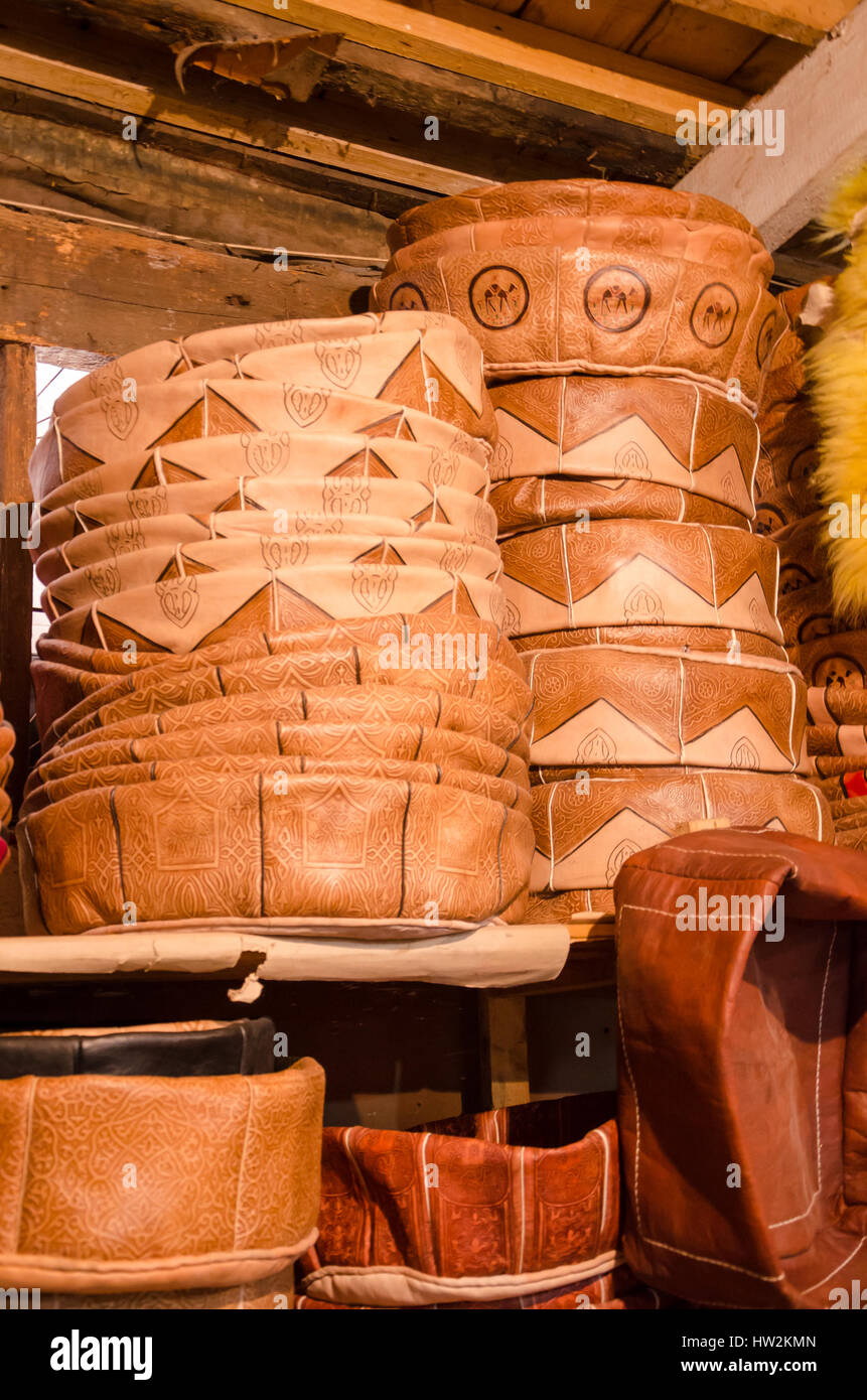 Handmade leather poufs stacked high in small traditional craft shop in ...