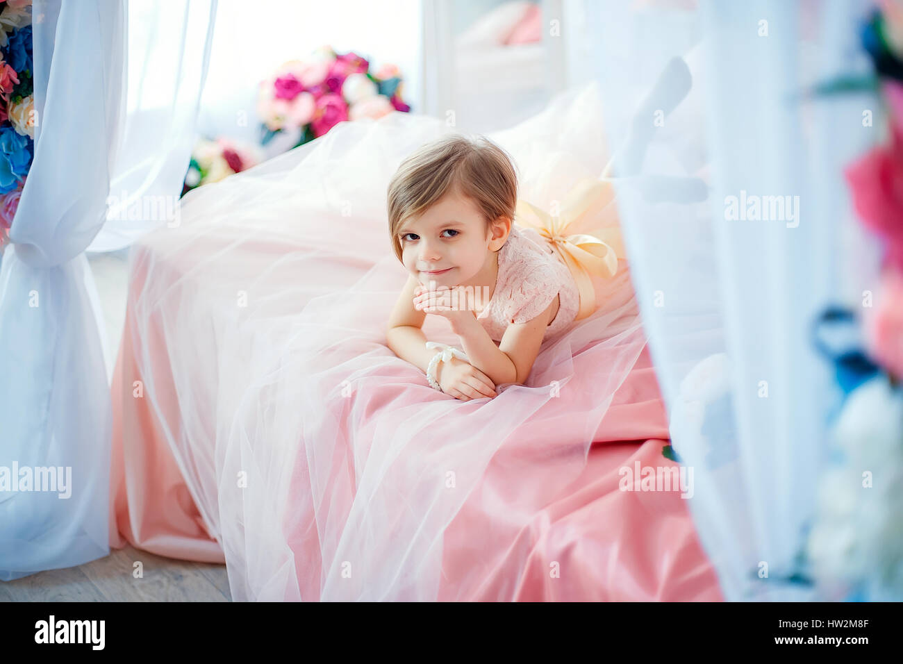 Little nice girl in dress lying on bed with flowers Stock Photo - Alamy