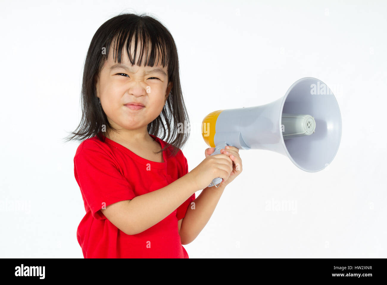 Portrait of a young little Chinese girl holding a megaphone in isolated ...