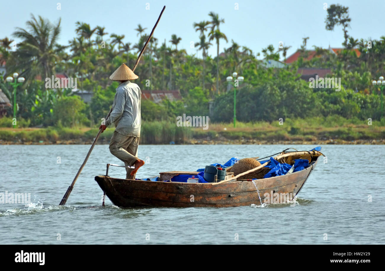 A fisherman paddles his boat home on the Hoi An river. Note how he ...