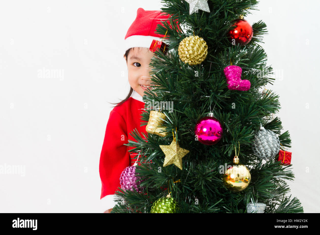 Asian Chinese little girl posing with Christmas Tree on plain white ...