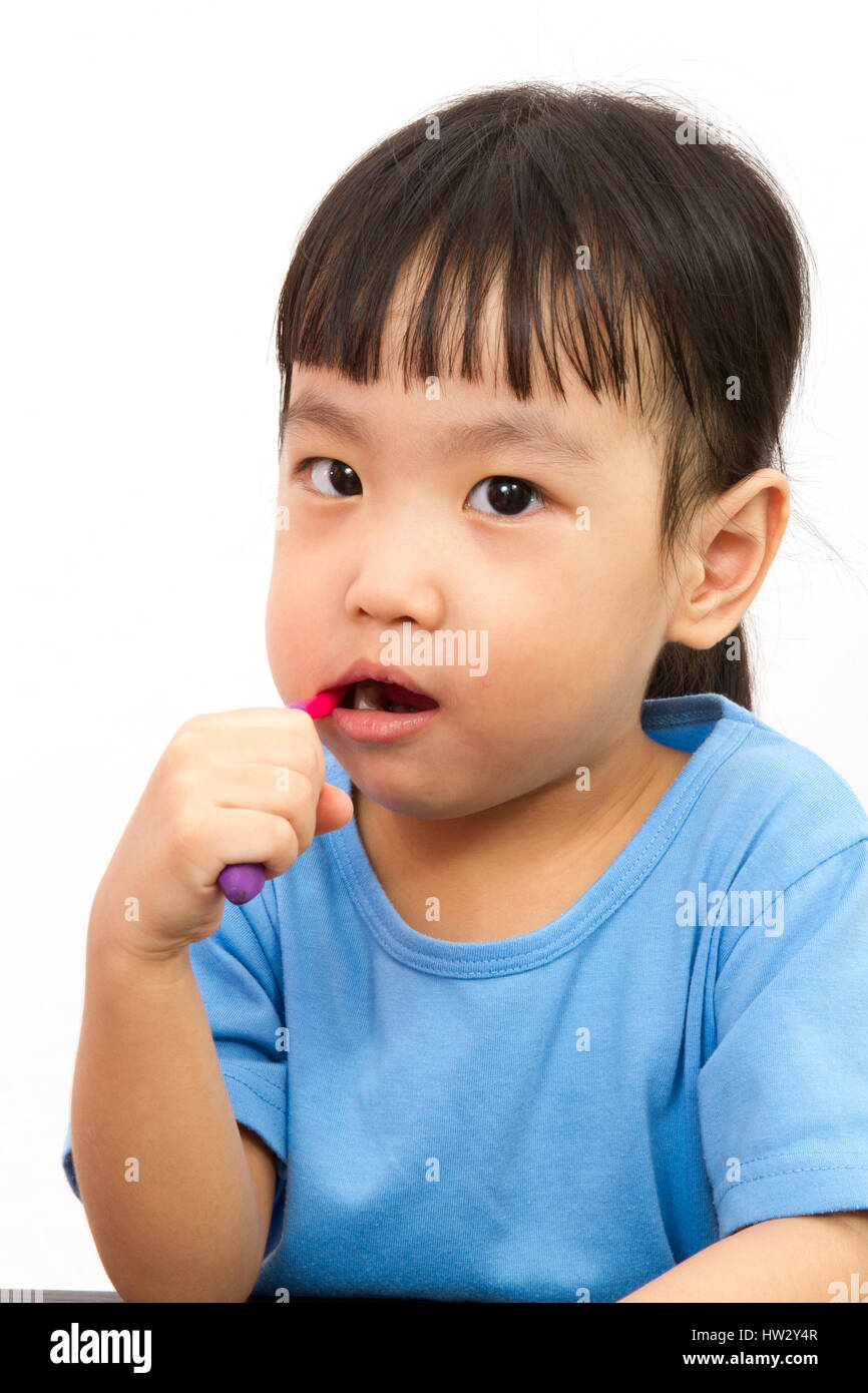 Chinese little girl brushing teeth in plain white isolated background ...