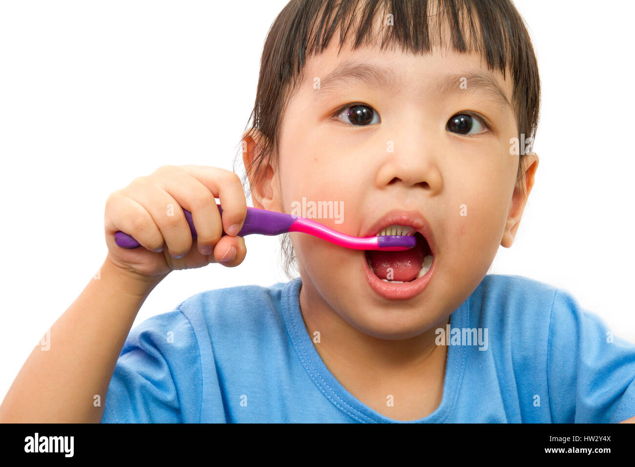 Chinese little girl brushing teeth in plain white isolated background ...