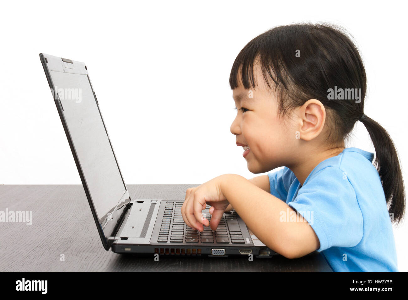 Chinese little girl using laptop in plain isolated white background ...