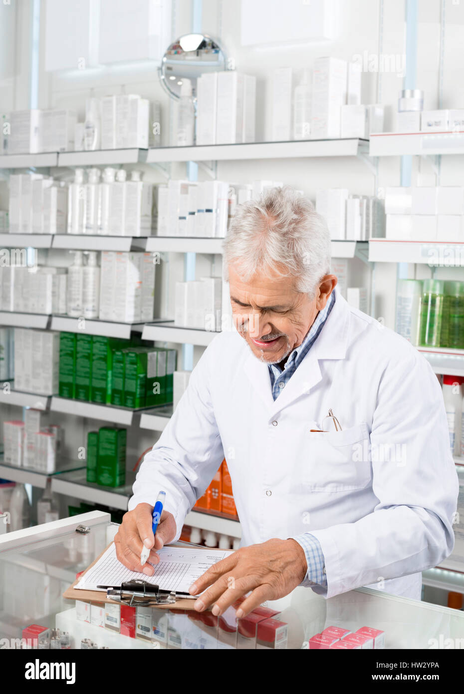 Senior male chemist writing on clipboard in pharmacy Stock Photo - Alamy
