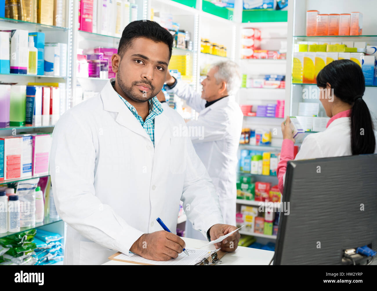Portrait of confident male chemist writing prescription on clipboard ...