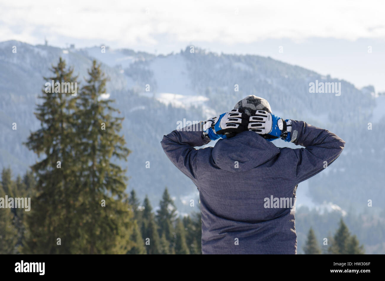 Back view of teenager man relaxed in winter jacket at mountains with ...