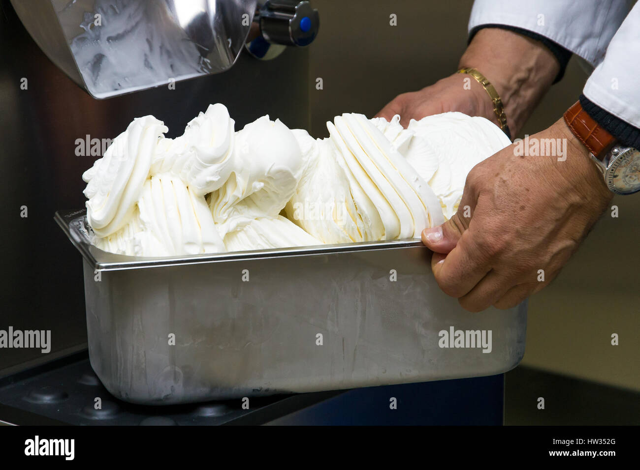 Human hands hold steel container full of vanilla flavour ice cream from ...