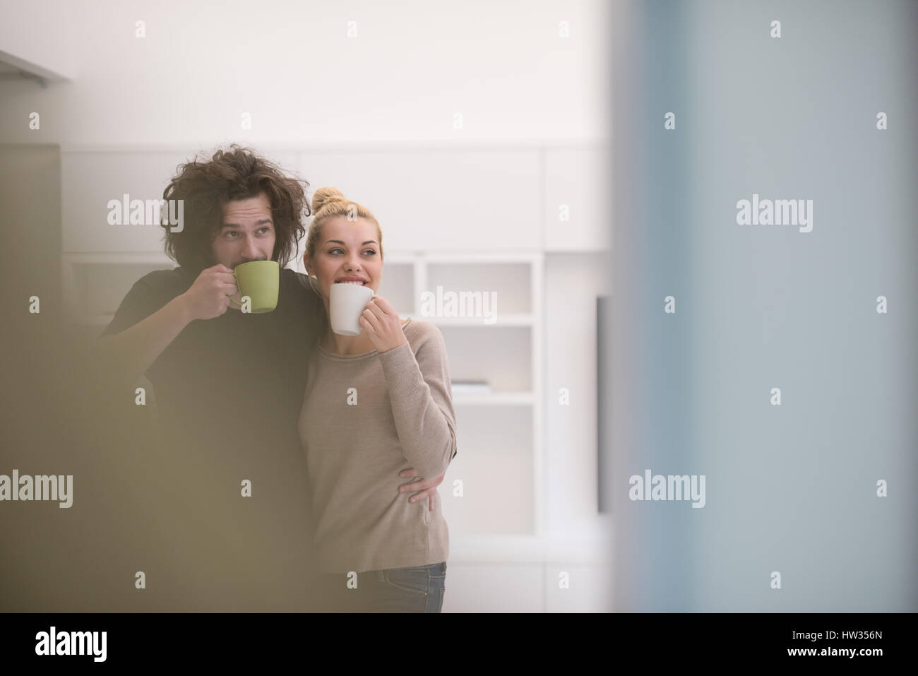 Portrait of a happy young beautiful couple hugging and drinking coffee ...