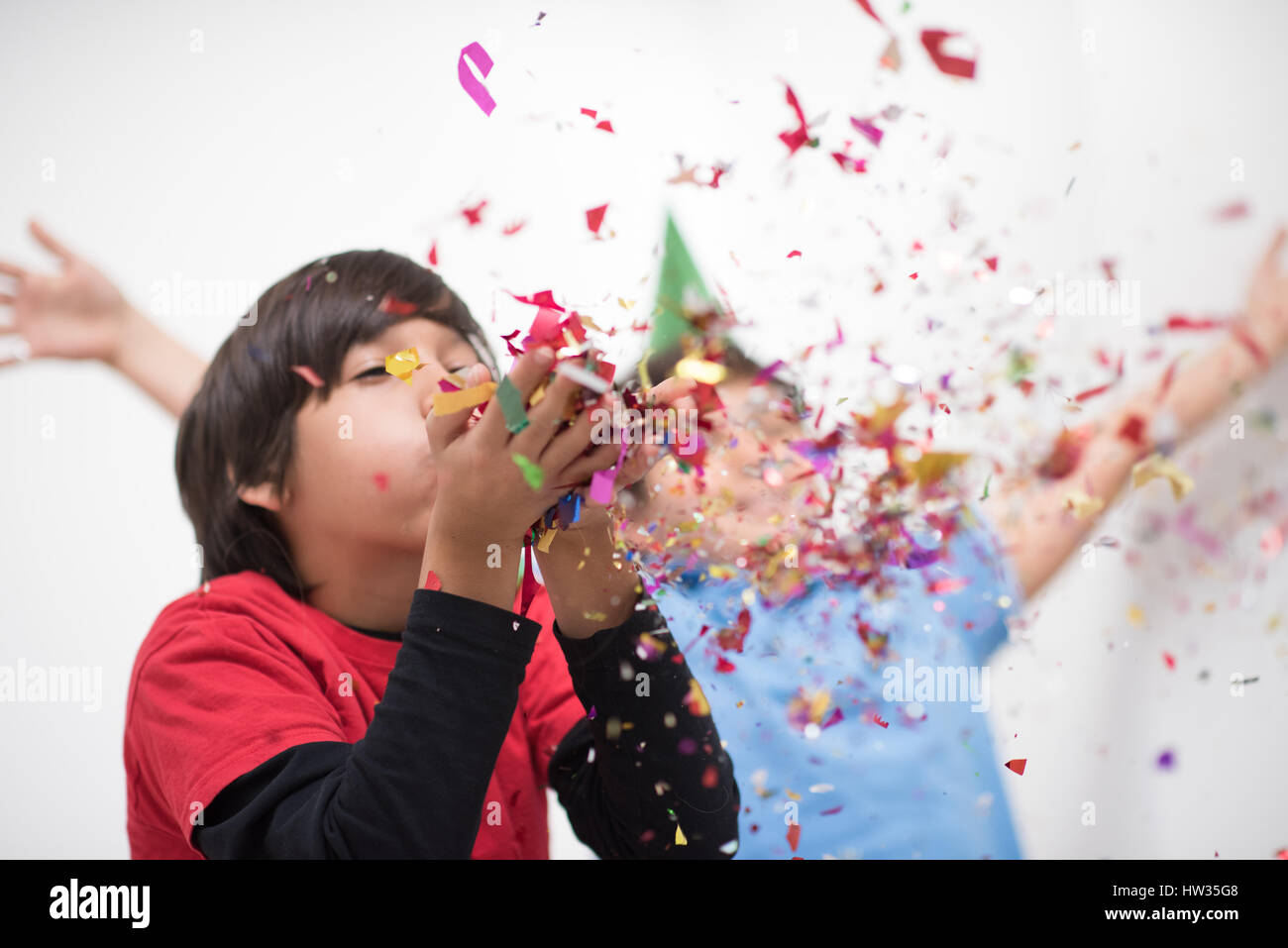 Happy kids celebrating party with blowing confetti Stock Photo - Alamy