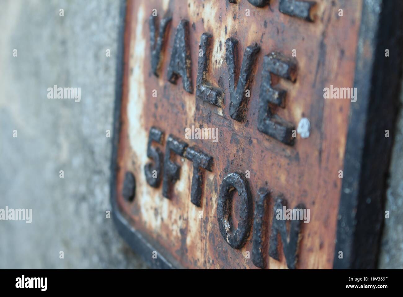 An old rusted sign indicating "Sluice Valve 5ft" is photographed ...