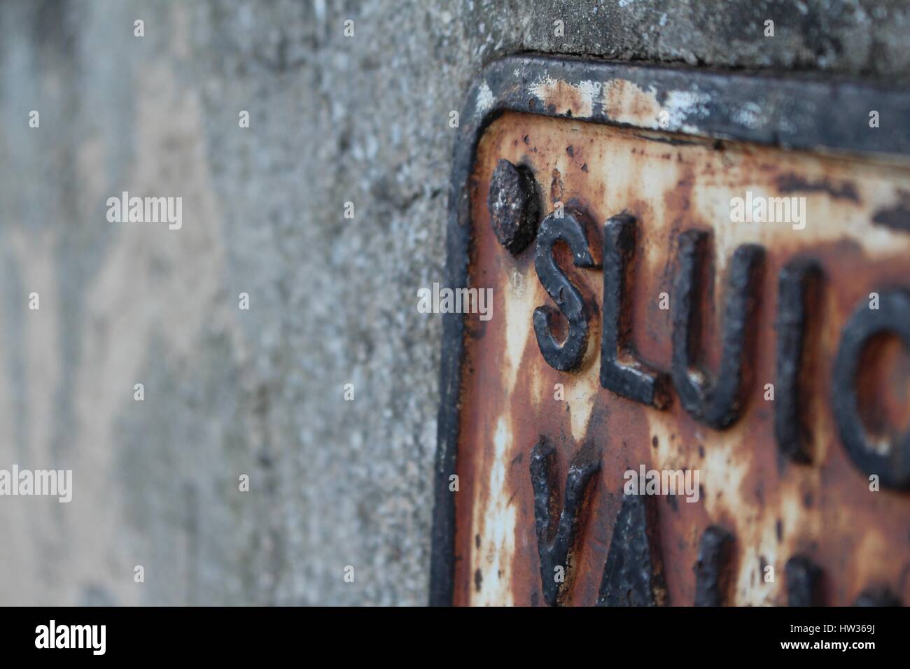 An old rusted sign indicating "Sluice Valve 5ft" is photographed ...