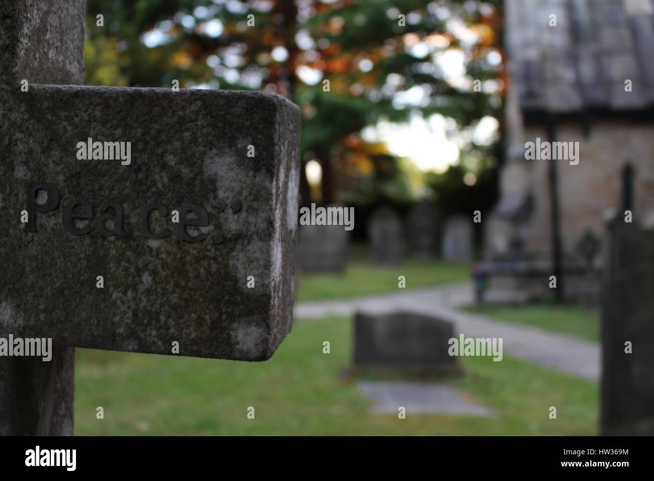 A grave with the inscription "Peace" stands in a graveyard while the ...