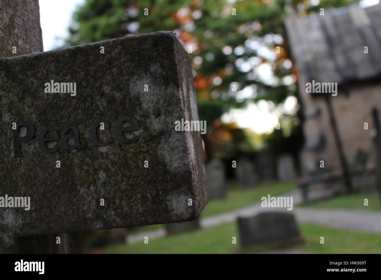 A grave with the inscription "Peace" stands in a graveyard while the ...