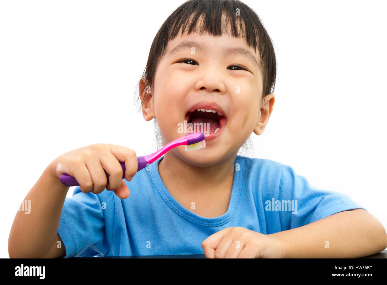 Chinese little girl brushing teeth in plain white isolated background ...
