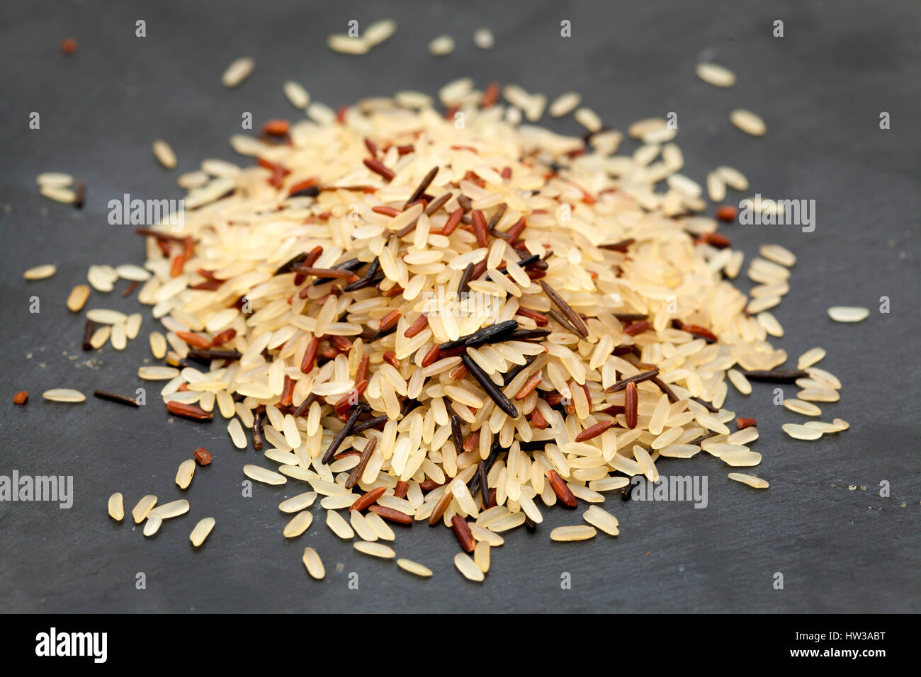 mixed rice, long grain basmati, red and wild, small pile on black slate ...