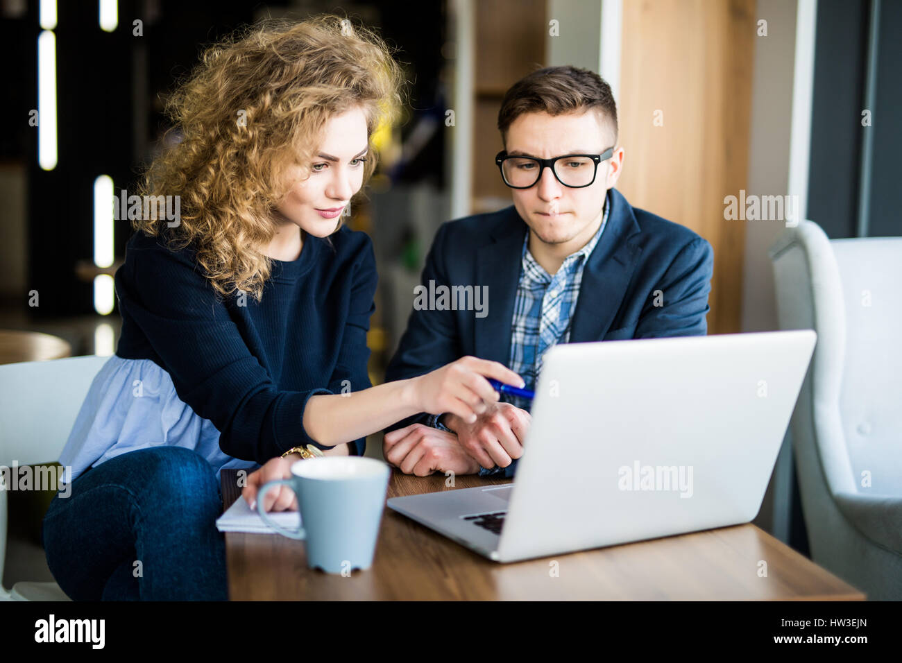 Group of two coworkers working over laptop discuss in a modern office ...