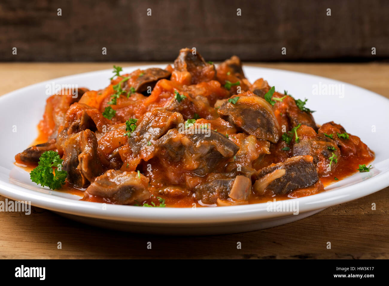 Chicken gizzard stew on plate with herbs on wooden rustic background ...