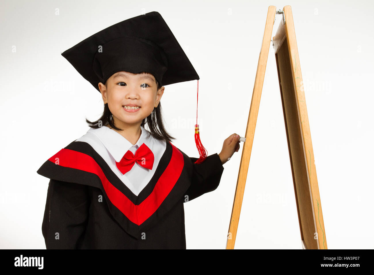 Asian Chinese children in graduation gown againts blackboard or ...