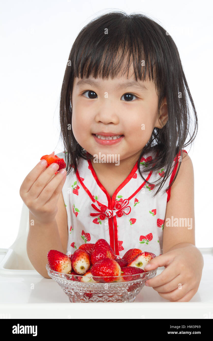 Asian Chinese children eating strawberries in plain white background ...