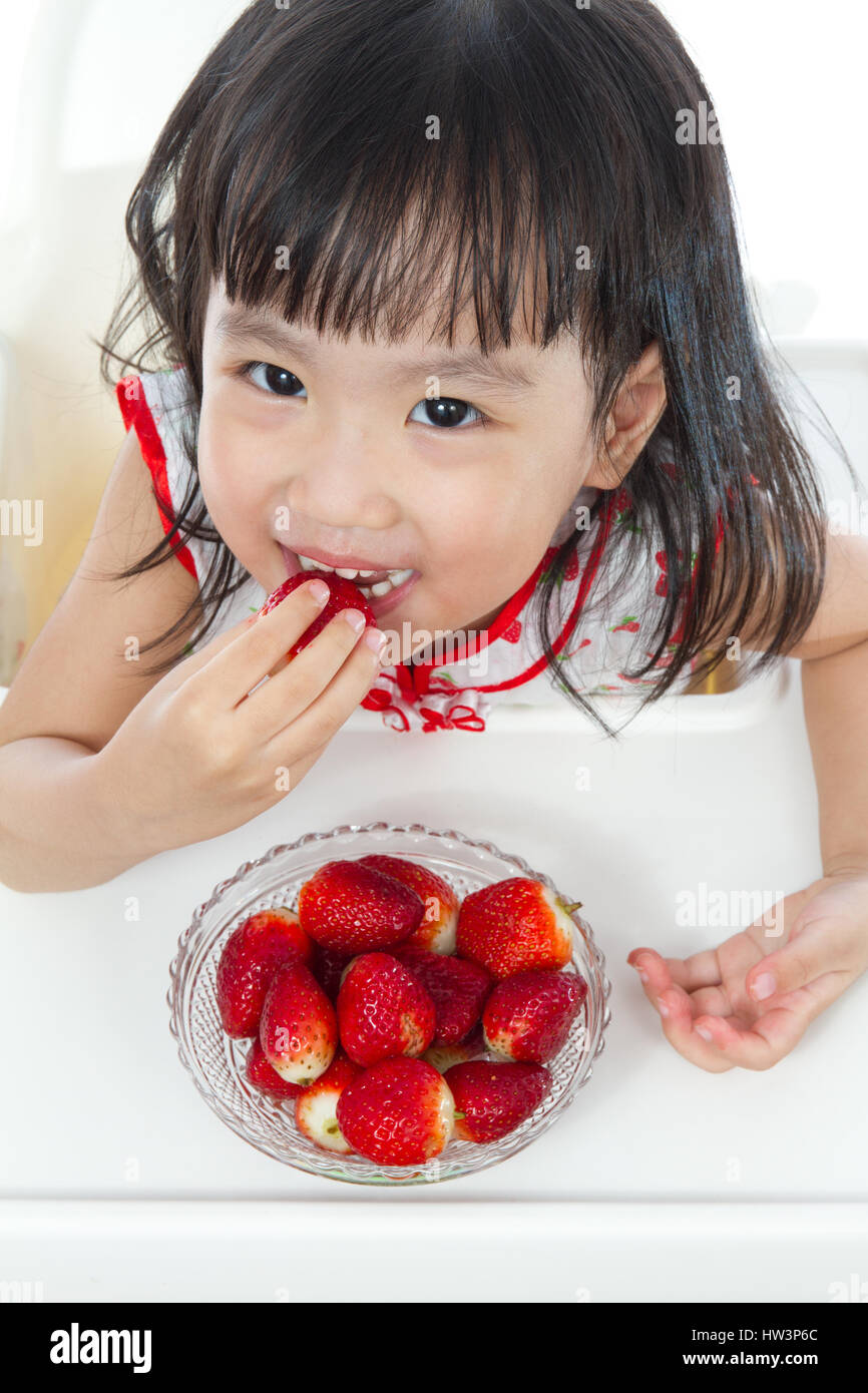 Asian Chinese children eating strawberries in plain white background ...