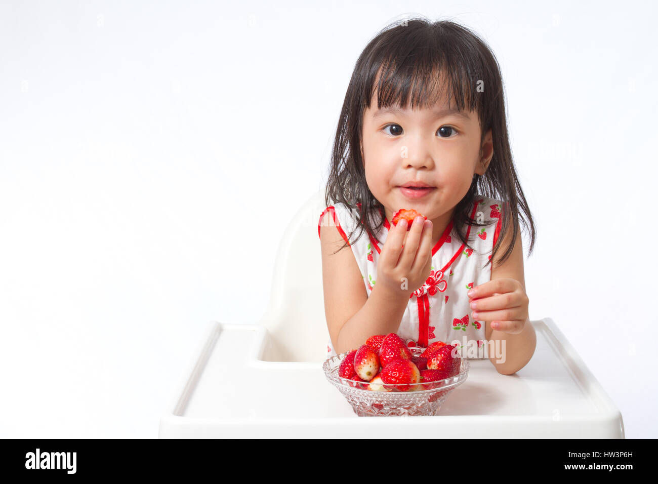 Asian Chinese children eating strawberries in plain white background ...