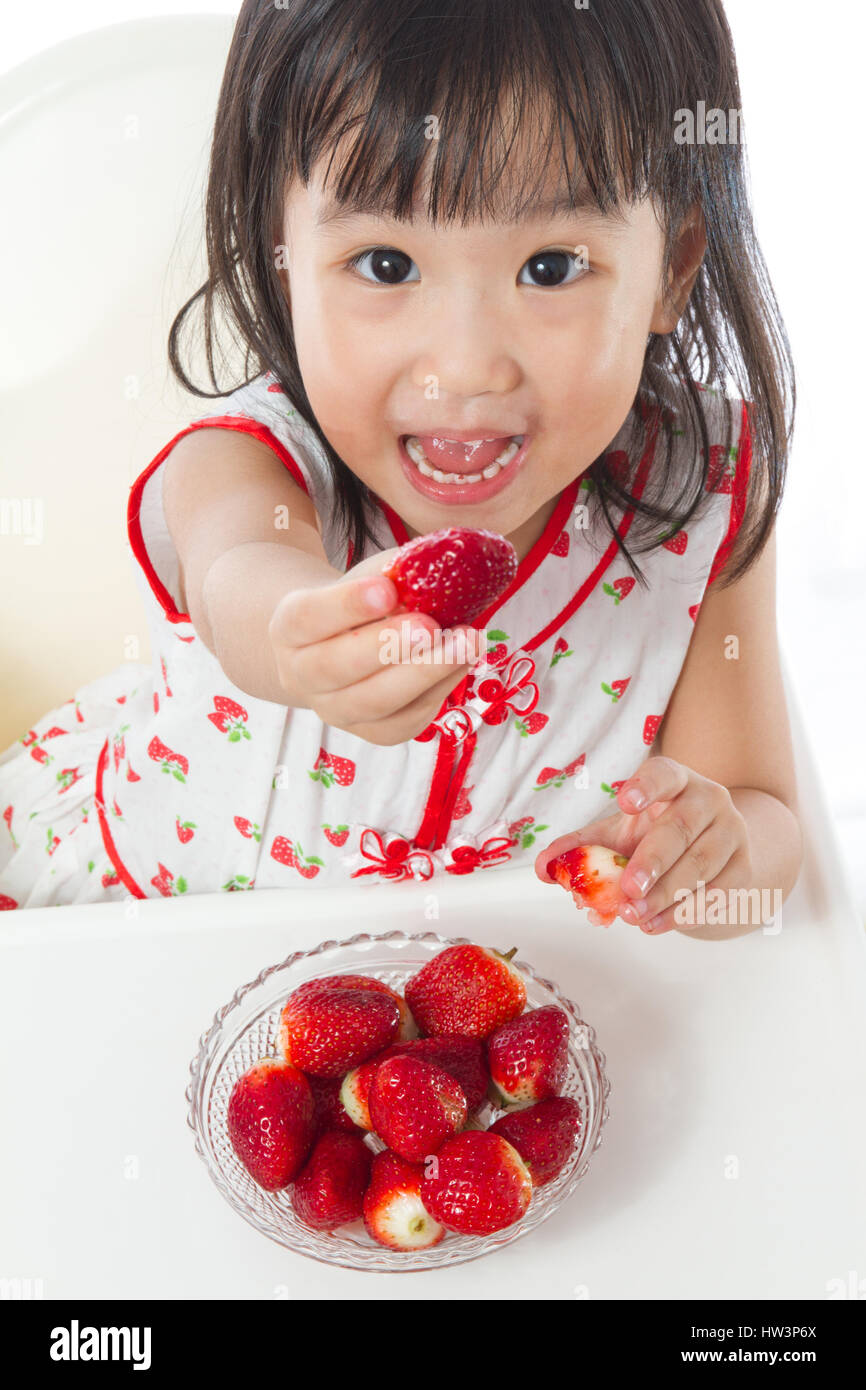 Asian Chinese children eating strawberries in plain white background ...