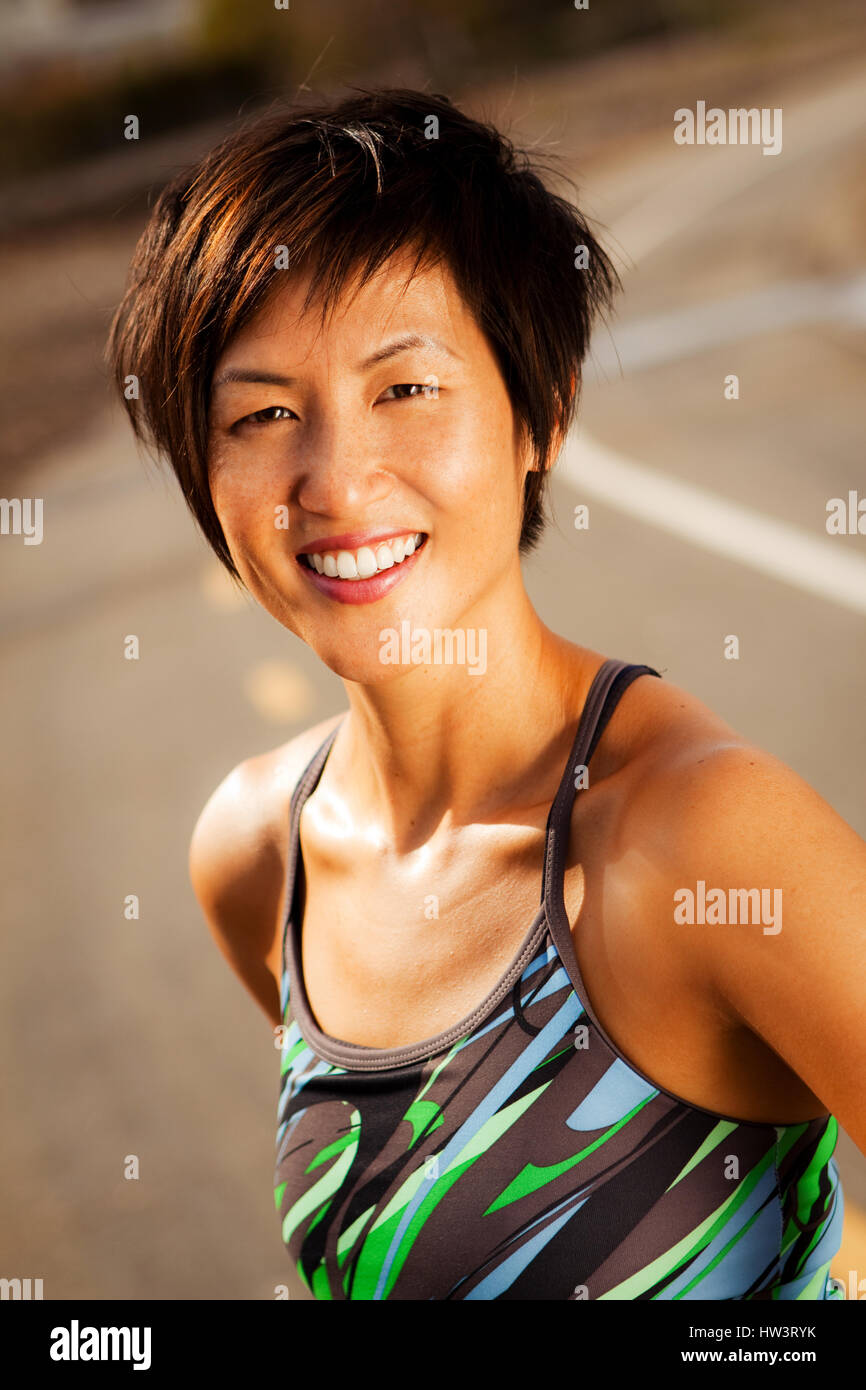 Fit Asian woman smiling outside Stock Photo - Alamy