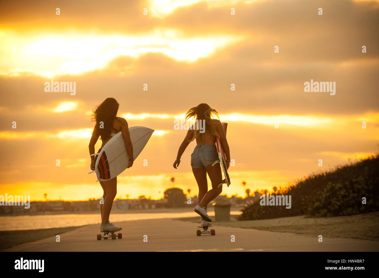 Teenage girls carrying surfboards on skateboards Stock Photo - Alamy