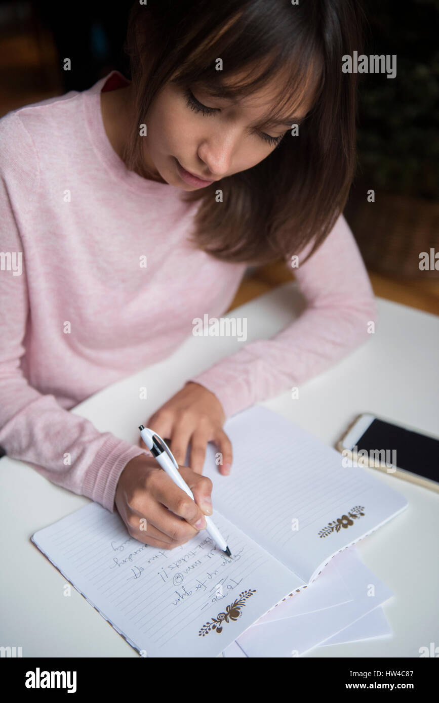 Mixed Race woman writing list in notepad Stock Photo - Alamy