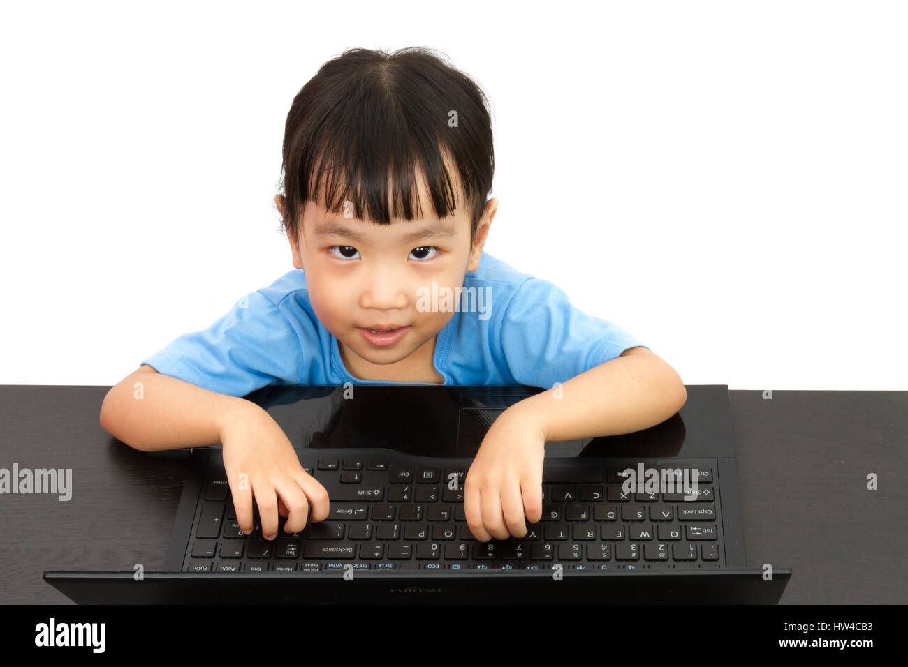Chinese little girl using laptop in plain isolated white background ...