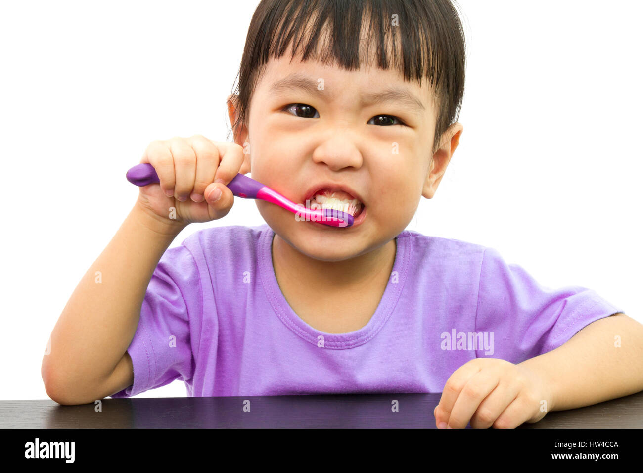 Chinese little girl brushing teeth in plain white isolated background ...