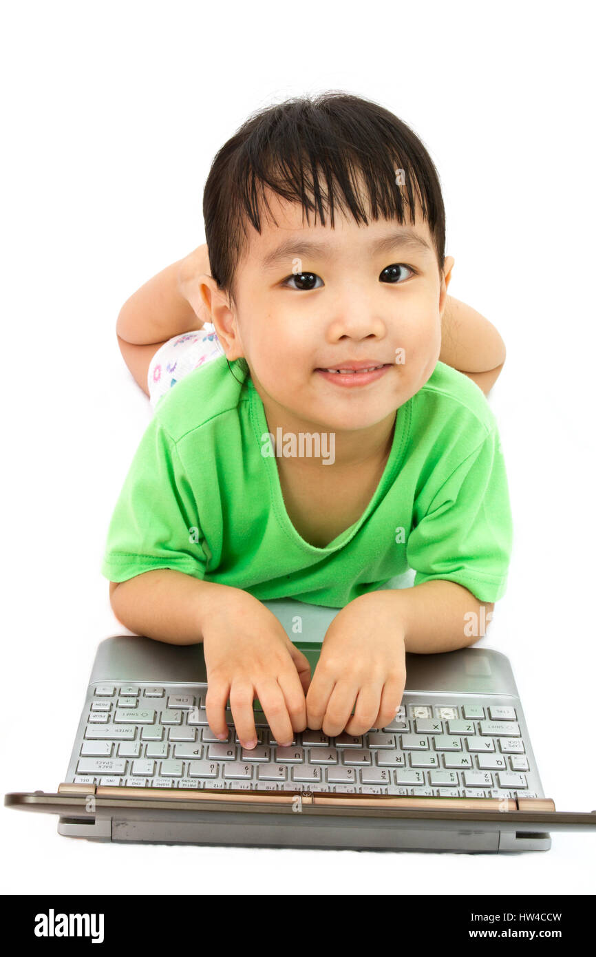 Chinese little girl lying down with laptop in plain white isolated ...