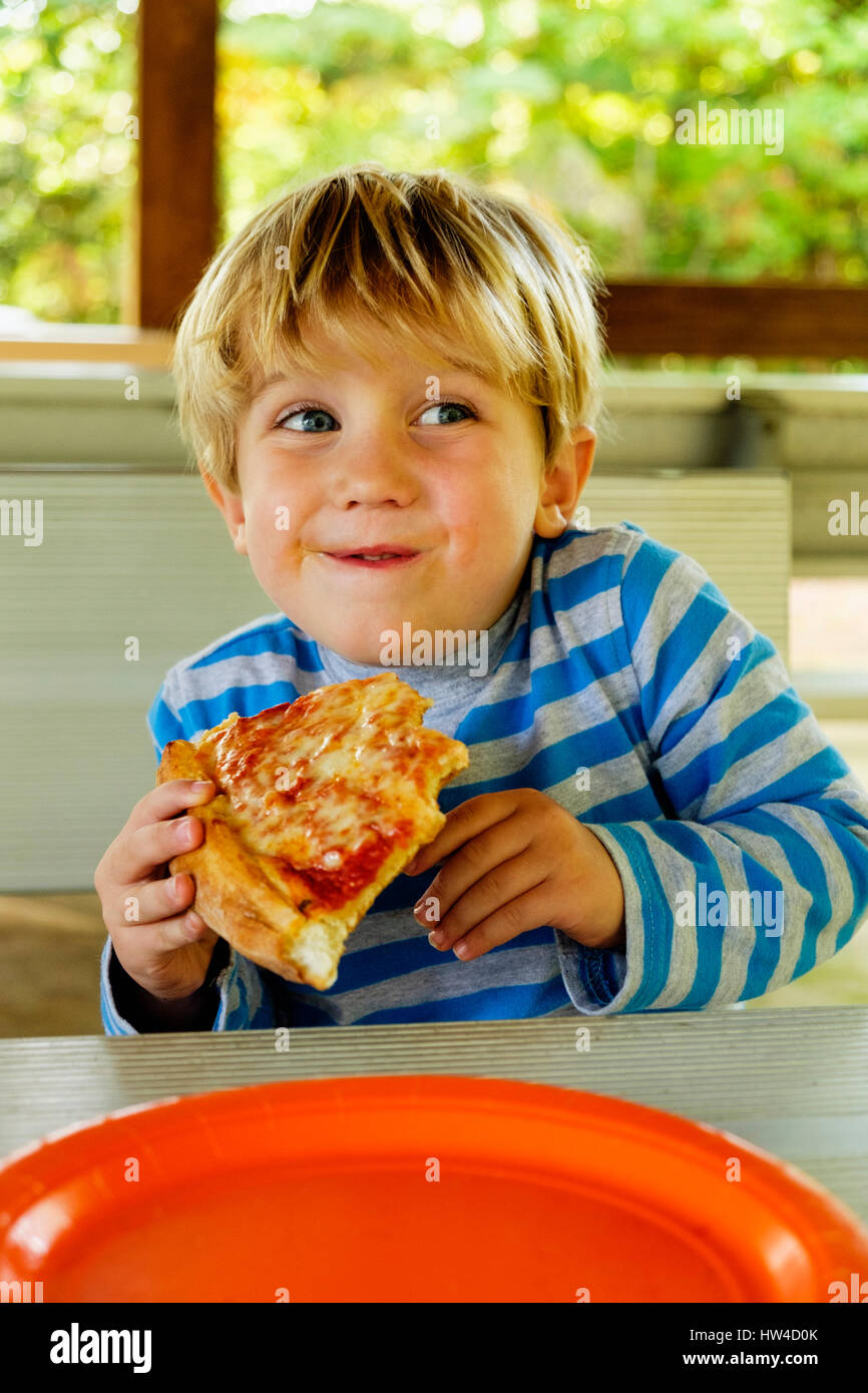 Playful Caucasian boy eating slice of pizza Stock Photo - Alamy