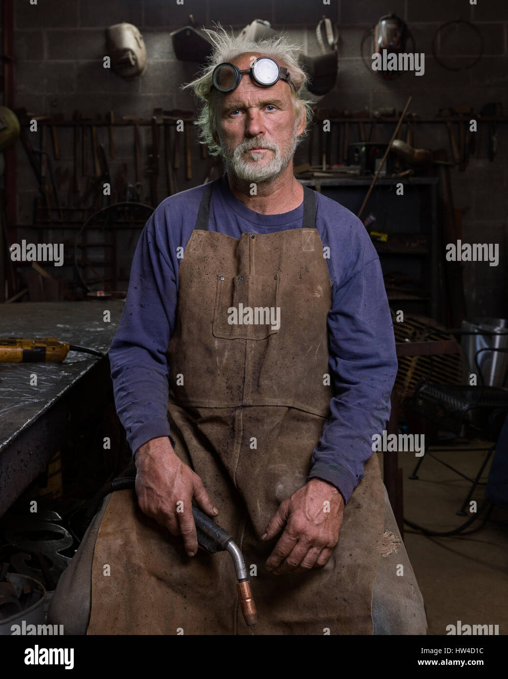 Portrait of serious Caucasian blacksmith in workshop holding torch ...