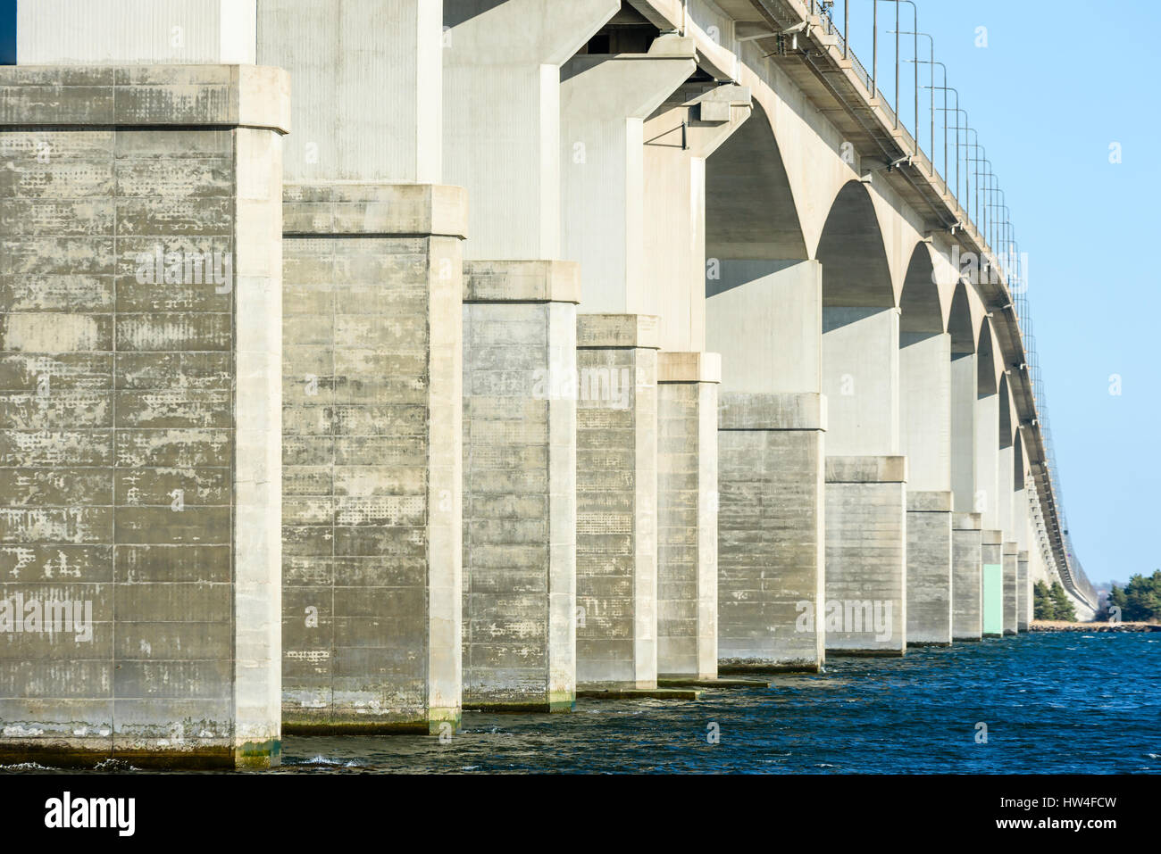 Concrete bridge over water. Gray pillars support the weight of the ...