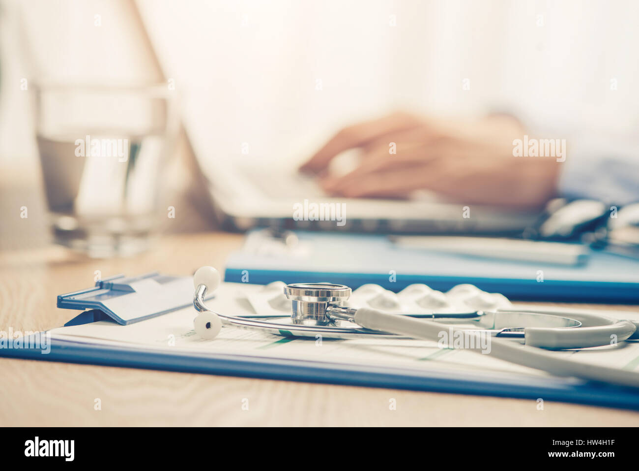Male doctor working at wooden desk in clinic Stock Photo - Alamy