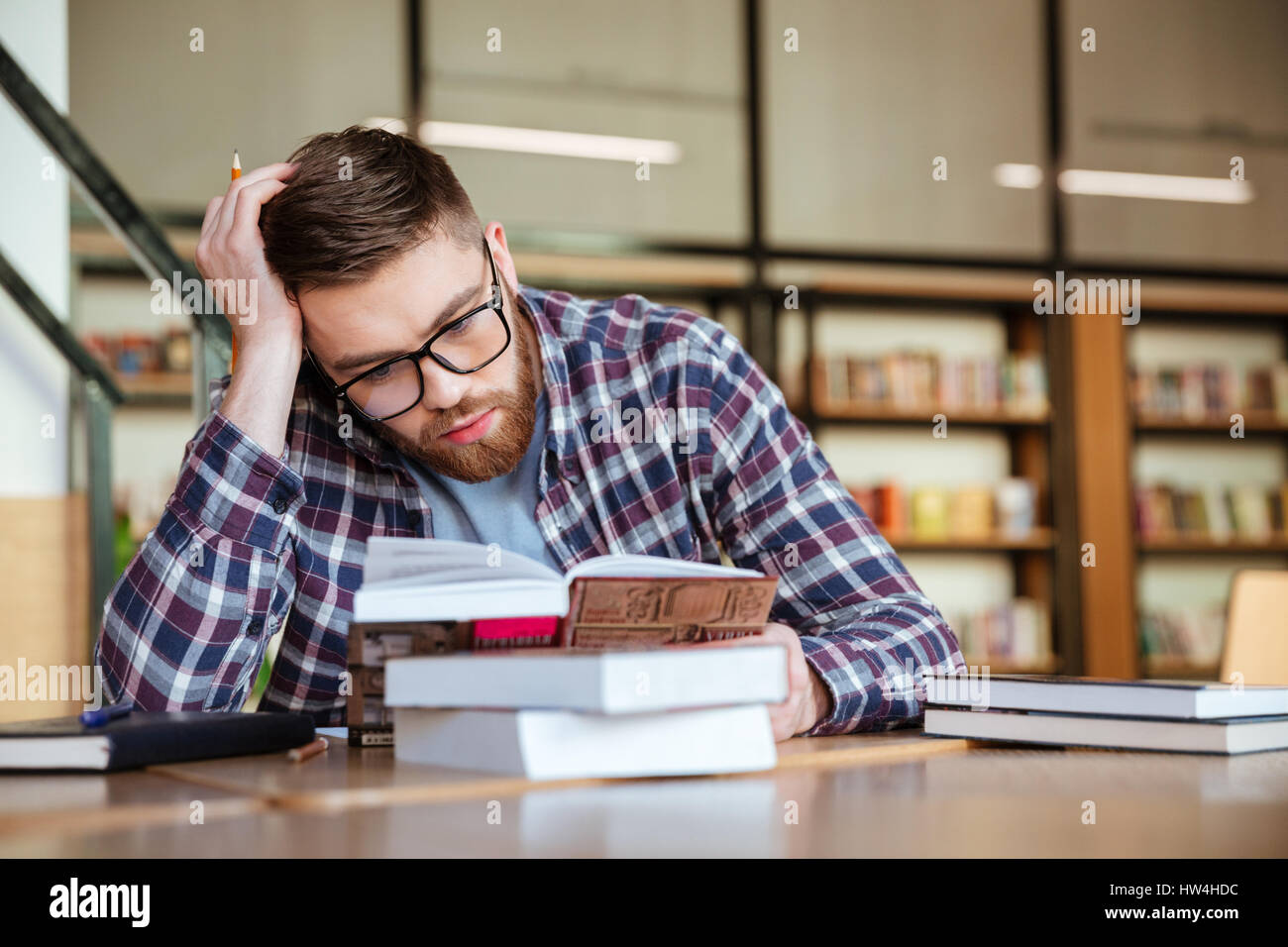Young guy student reading book with serious face in the library Stock ...